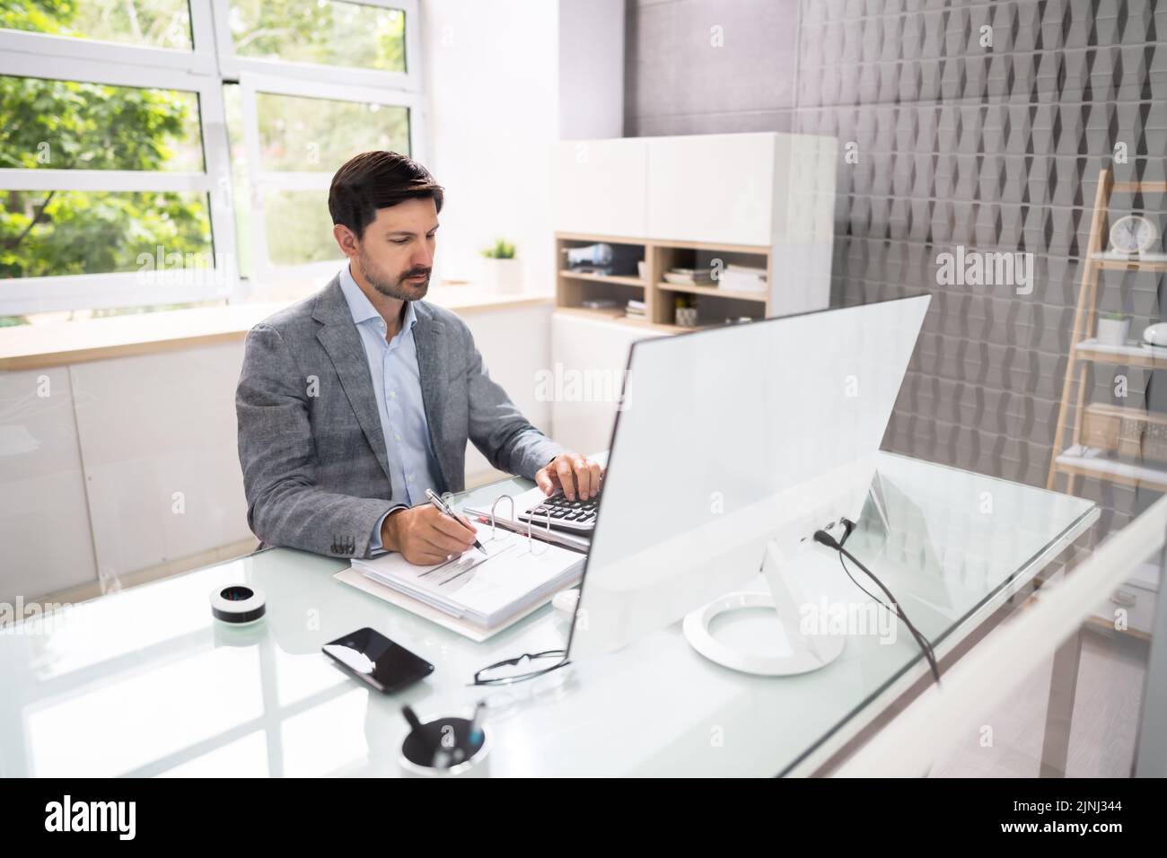 Businessperson Calculating Invoice With Computer On Desk Stock Photo ...