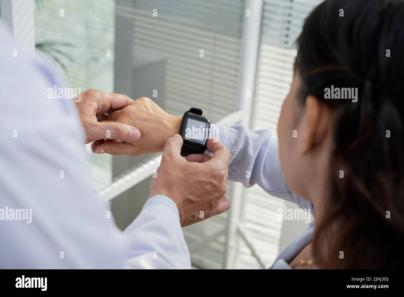 Over shoulder view of friendly therapist showing his senior patient how ...