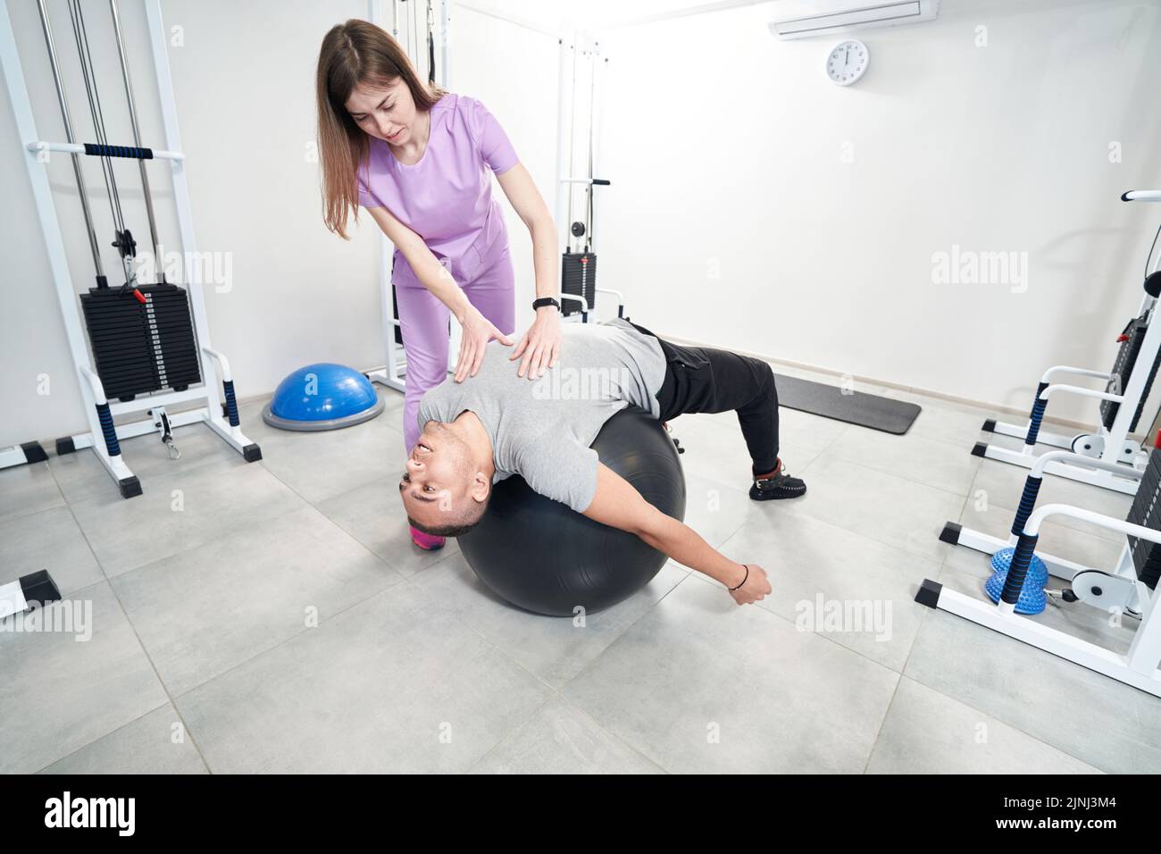 African American man doing physical therapy exercise with instructor ...