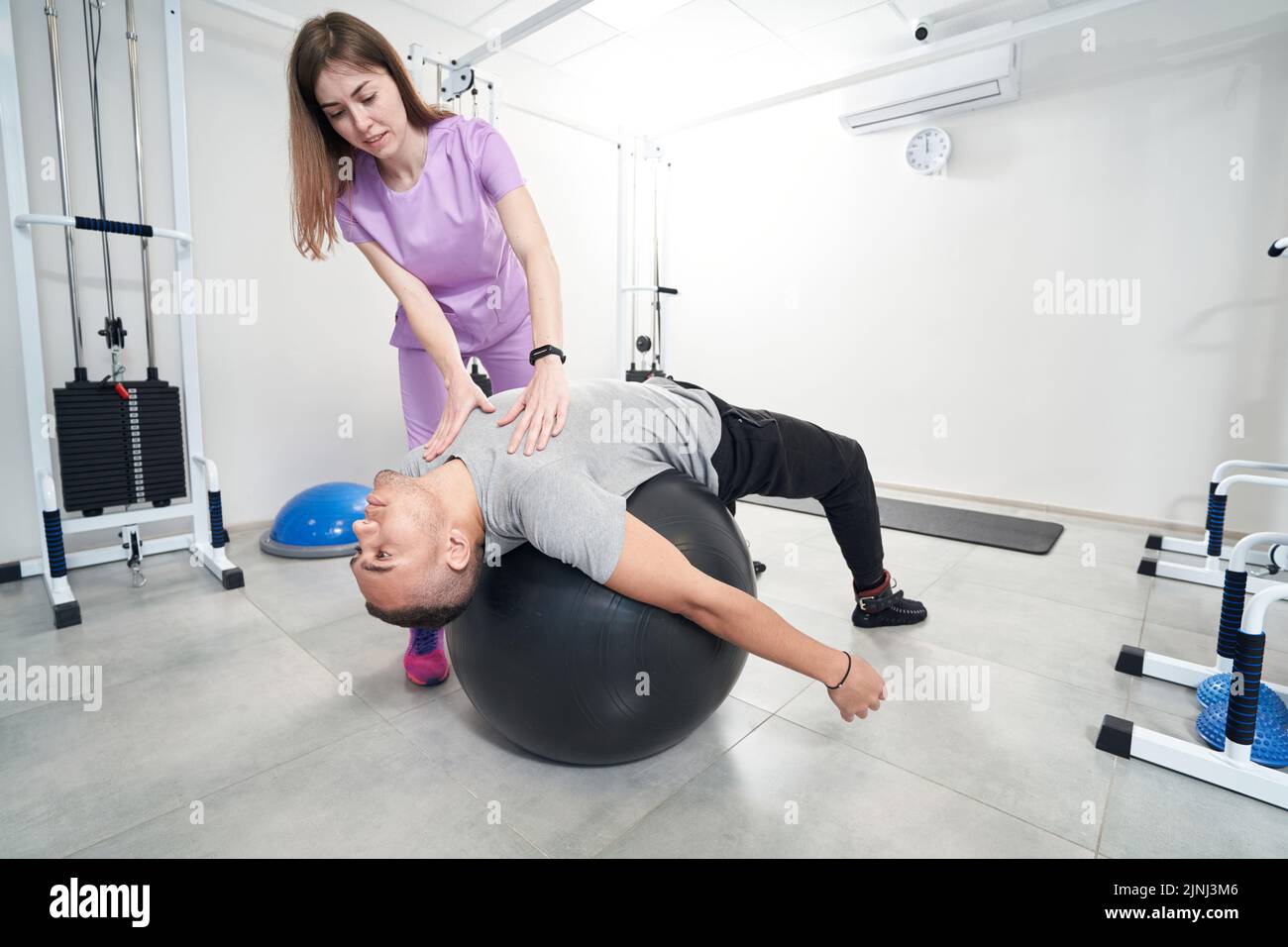 Female doctor helping man to perform physical therapy exercise Stock ...