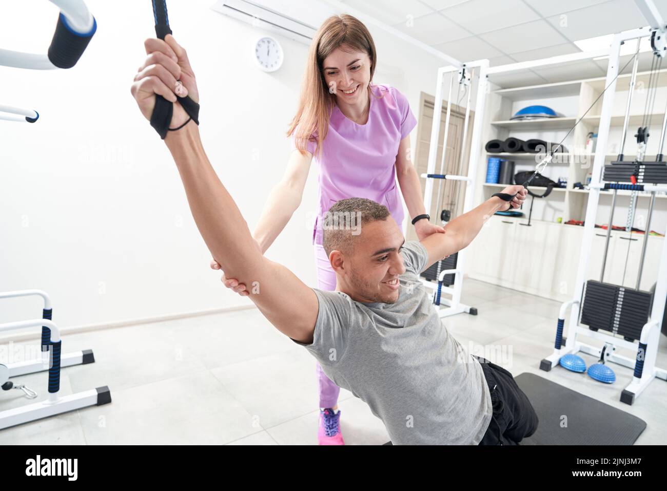 Cheerful man doing physical therapy exercise with female doctor Stock ...
