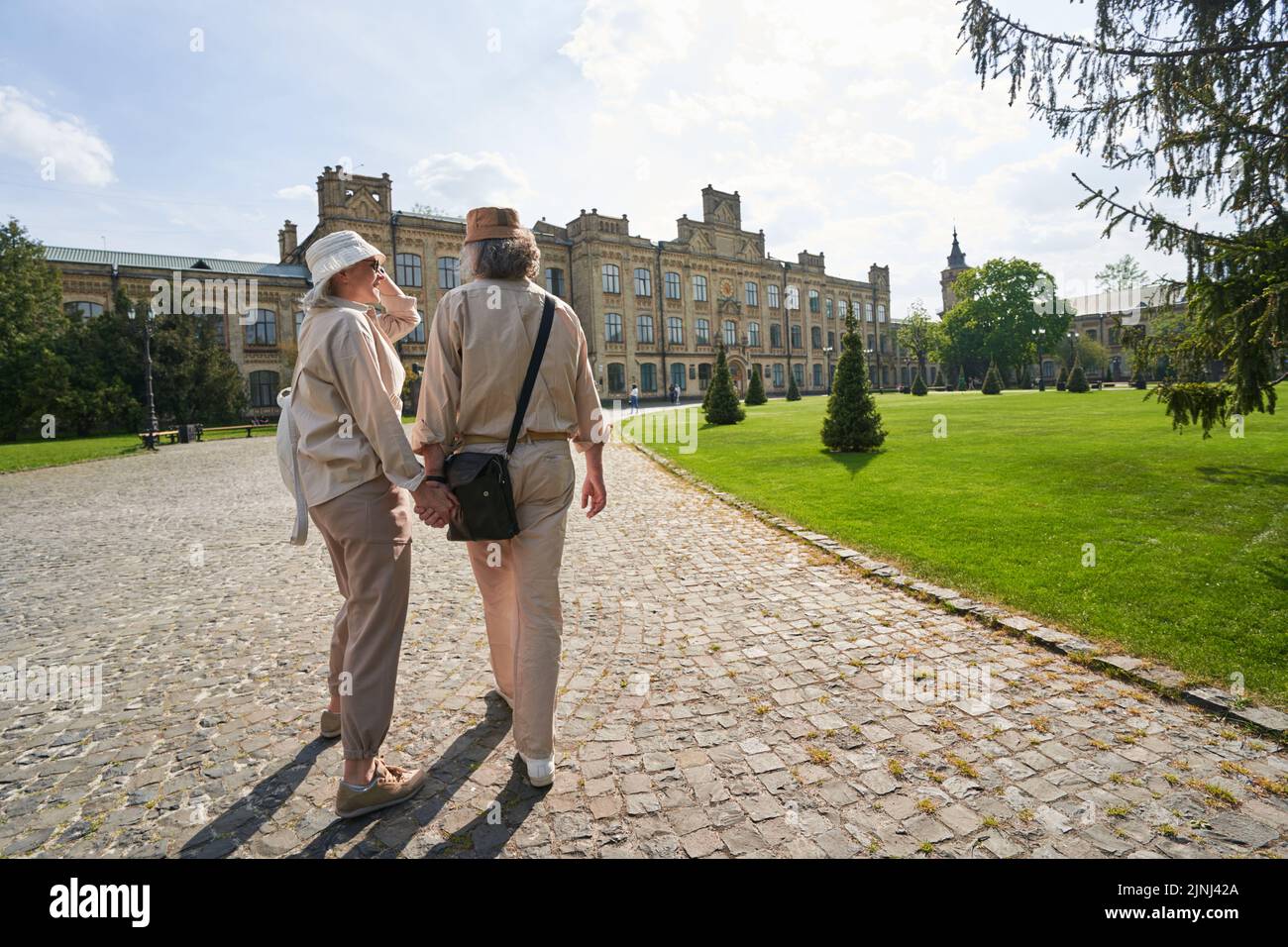Joyful female person putting hand on hat during walk Stock Photo - Alamy