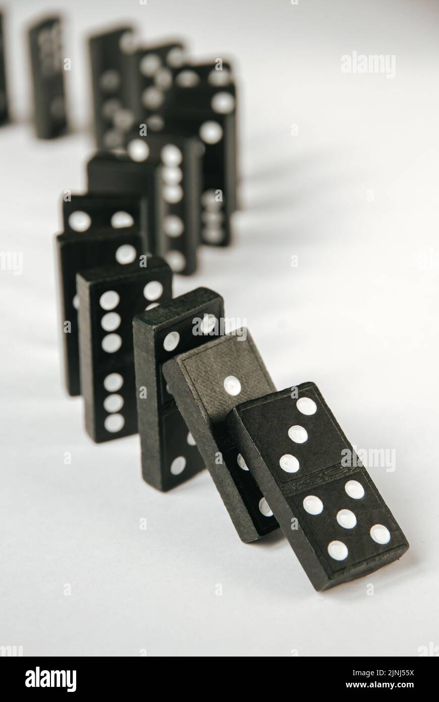 Black dominoes chain on a white table background. Domino effect concept ...