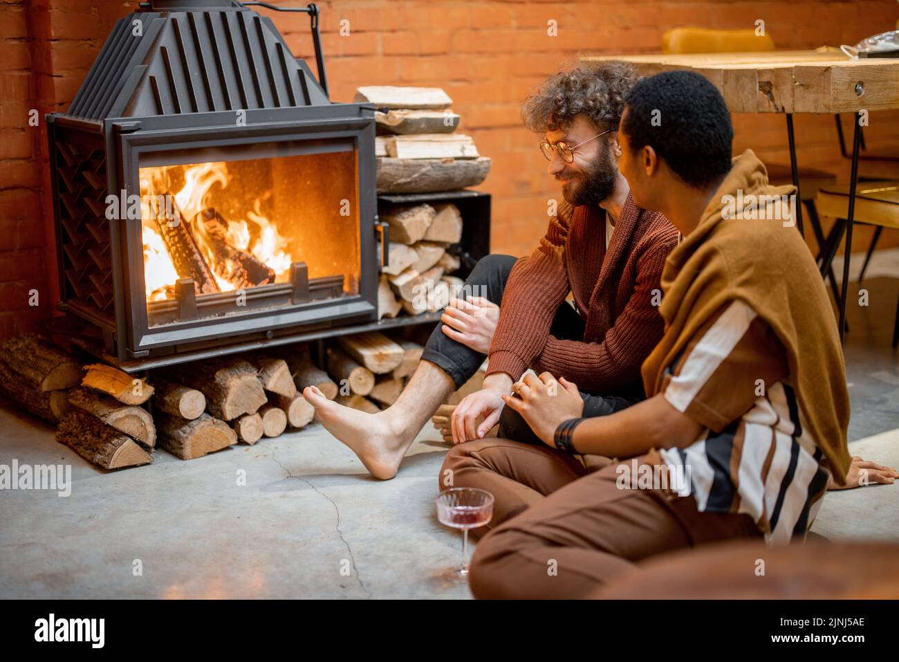 Two men sitting together by the burning fireplace at cozy home Stock ...