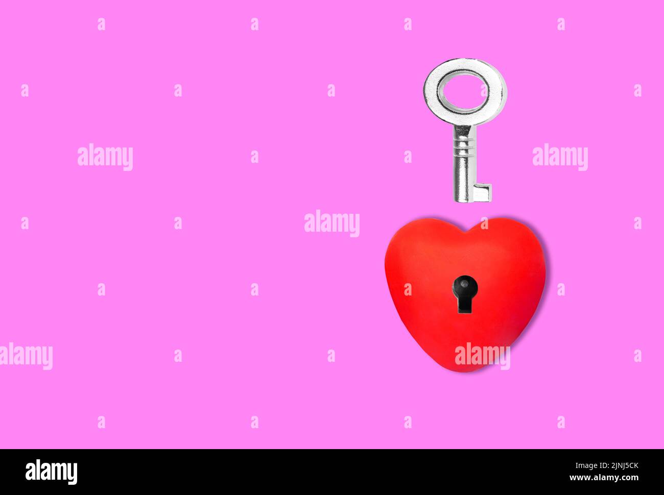 Heart with a keyhole and a skeleton key isolated on pink background ...