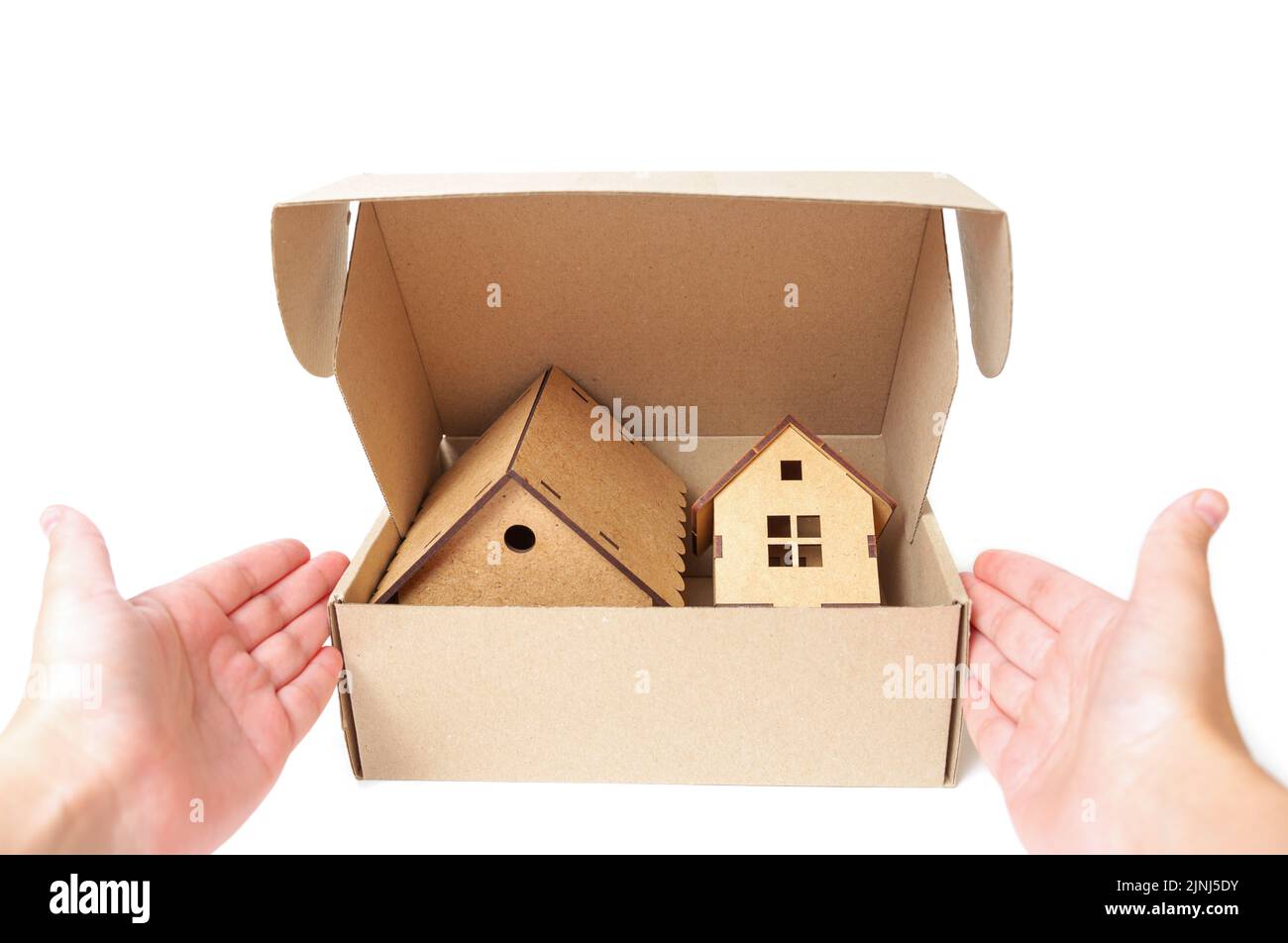Hand unpacking a shipping box with wooden toy houses isolated on white ...