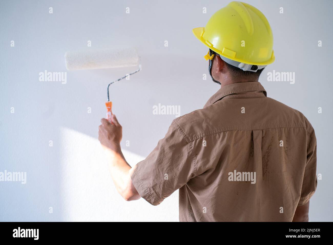Painter man painting on white wall interior working new house with ...