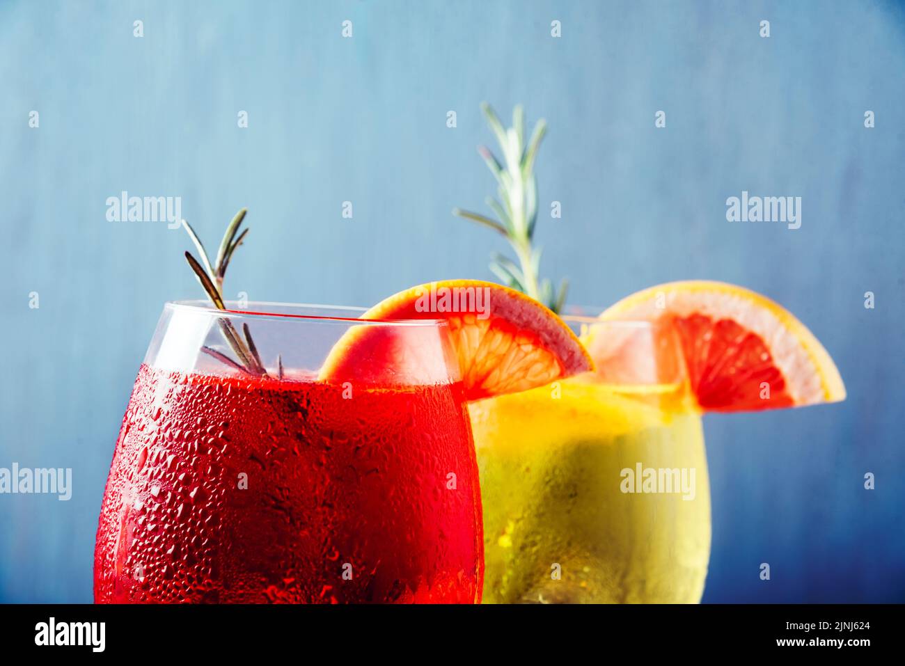 Tow glasses of red and yellow aperol spritz cocktail with rosemary and ...