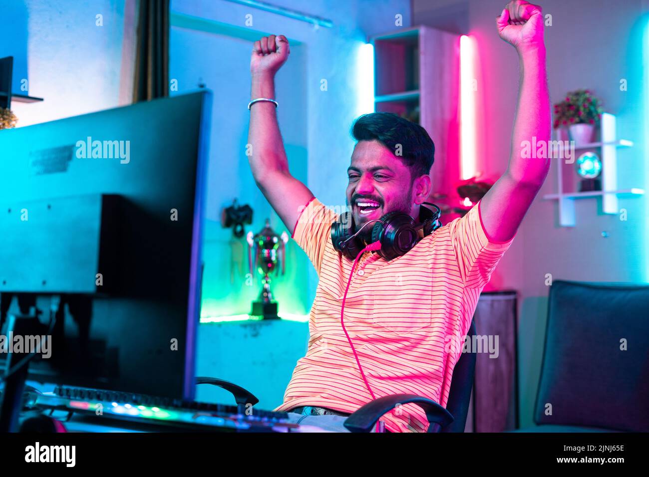 Cheerful gamer celebrating win by raising hands while playing online ...