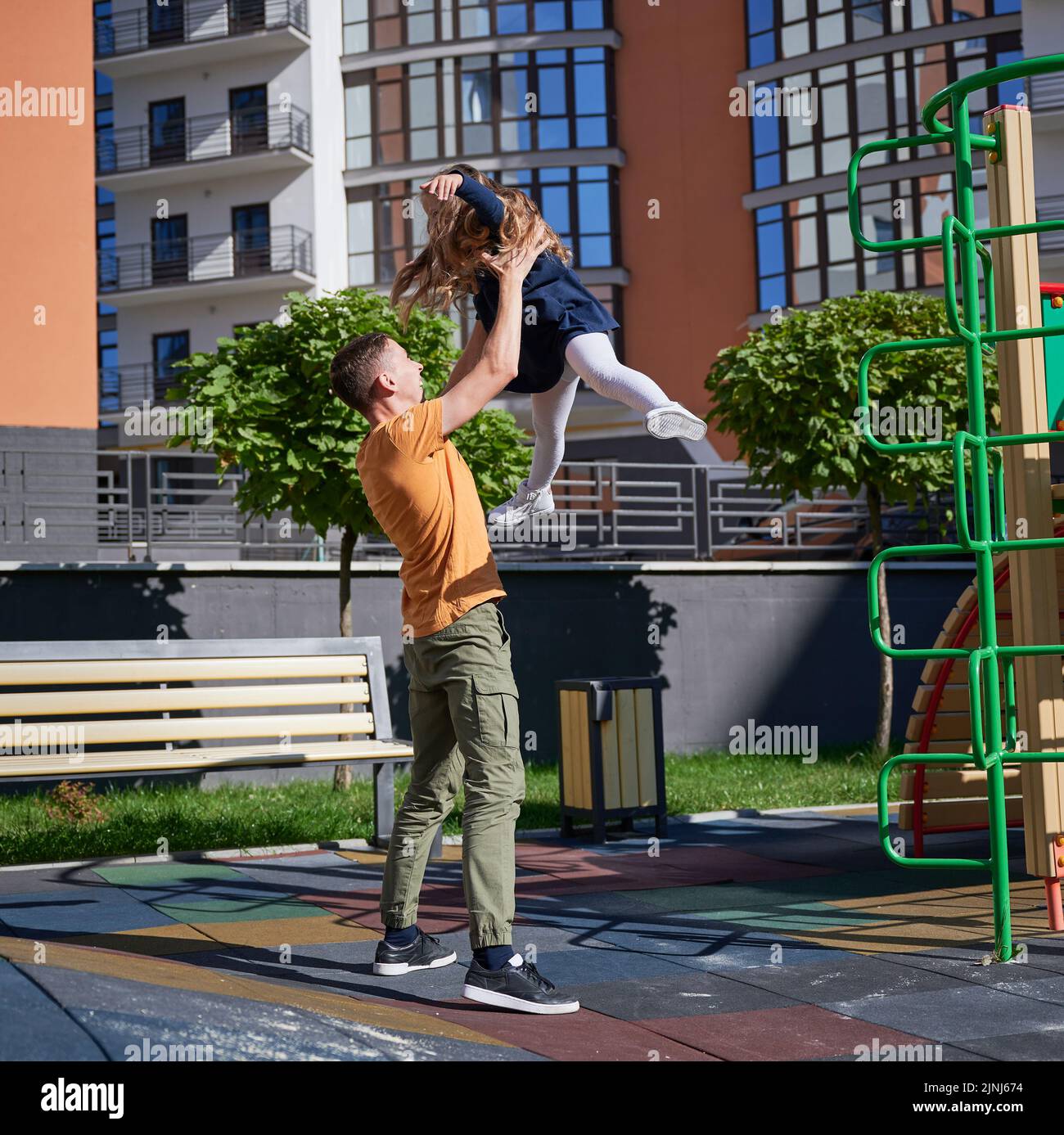 Happy father catching cheerful daughter, jumping from ladder at ...