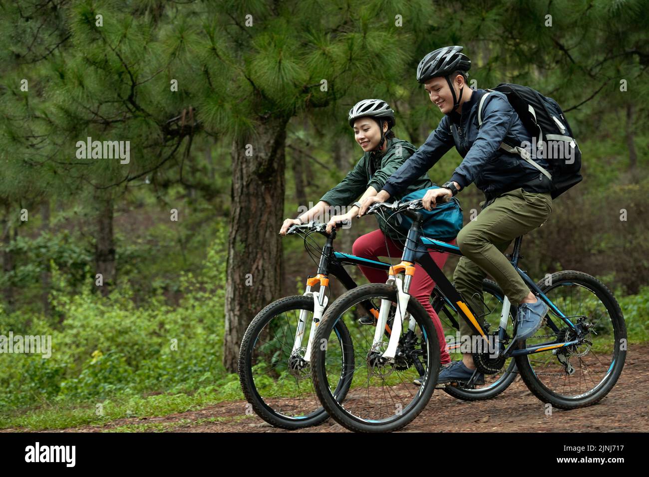 Side view of young Asian couple wearing helmets while practicing cross ...