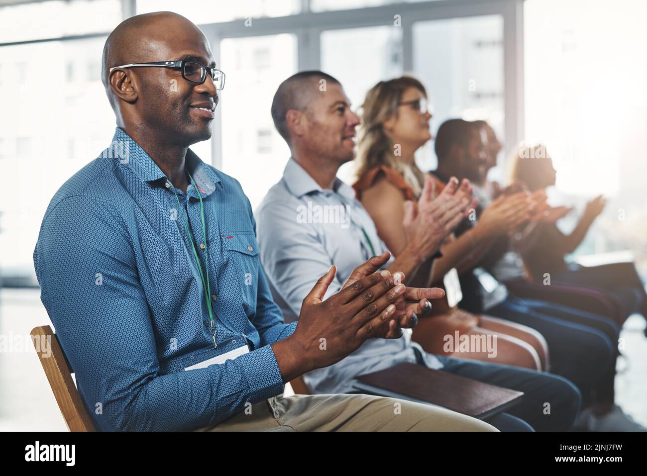 Employees sitting and clapping together in a seminar and successful ...