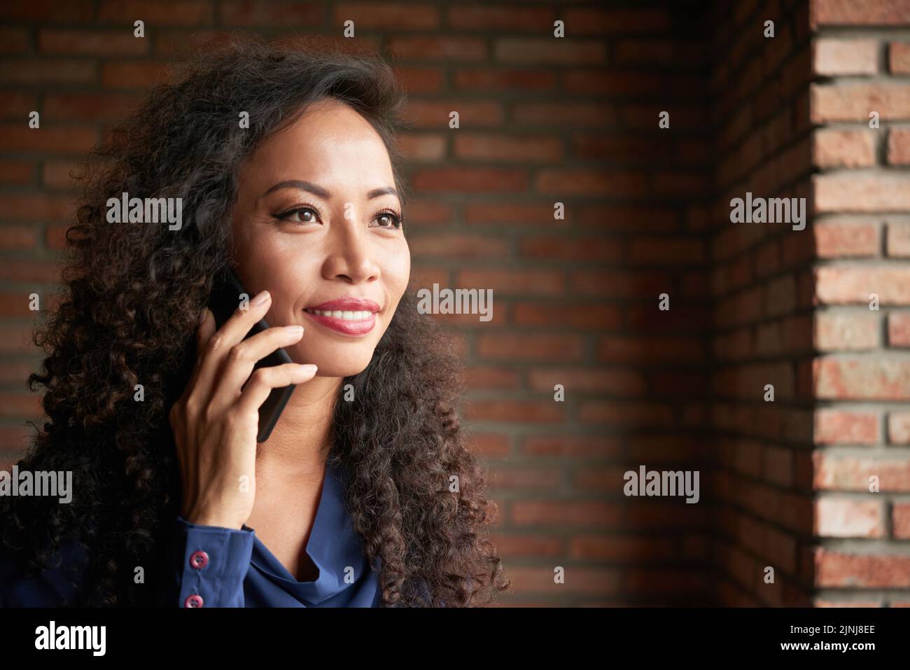 Head and shoulders portrait of attractive Asian woman looking away with ...