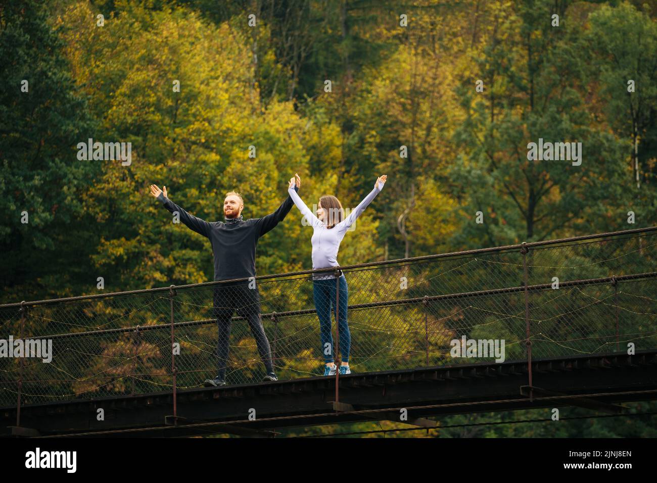 Healthy lifestyle. Young man and woman standing with arms raised on a ...