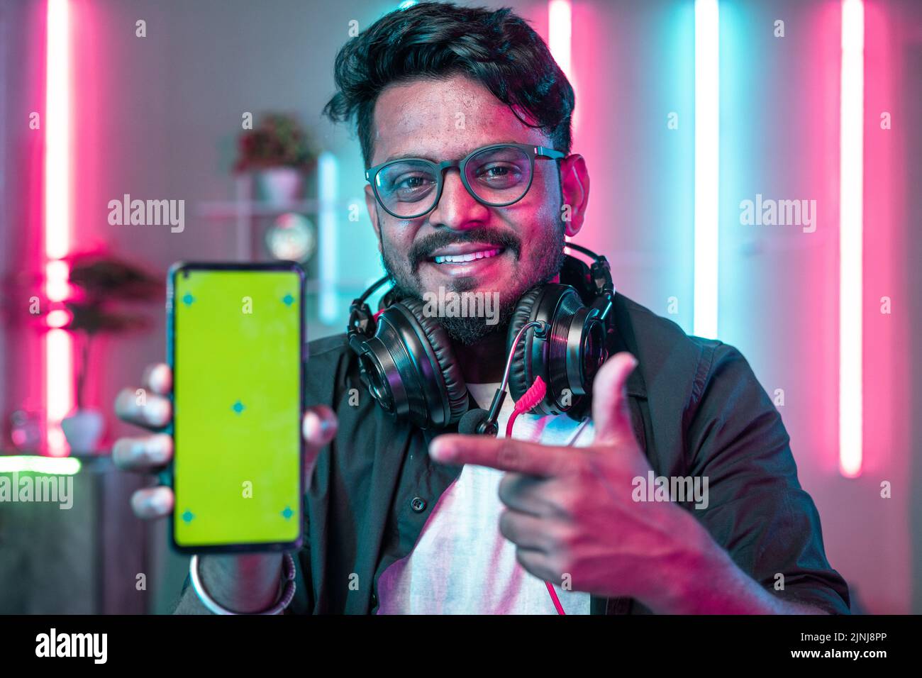 Professional gamer with headset showing green screen mobile phone by ...