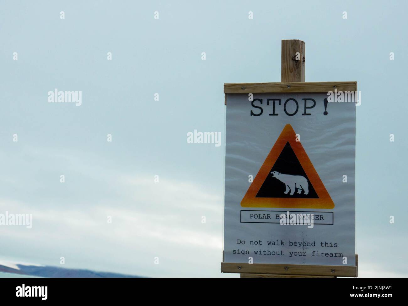 Attention, polar bear. Warning sign against gray sky. Seen in Ny ...