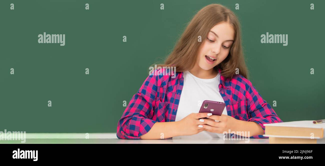 happy kid chatting on smartphone in classroom at blackboard, message ...