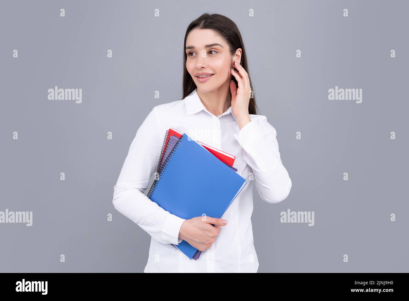 Smiling young woman college student holding book on isolated gray ...
