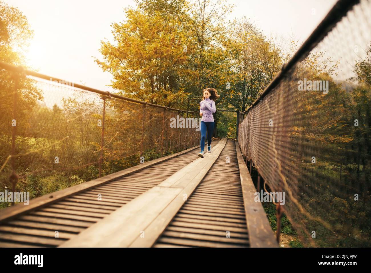 Young woman spends time with benefit. Female runner begins to jog over ...
