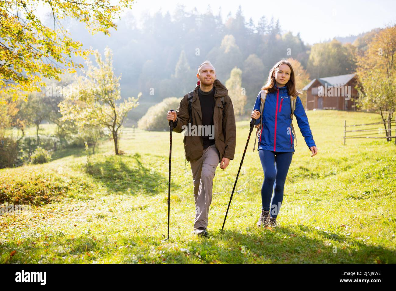 Man and a woman with backpacks on their shoulders and with trekking ...