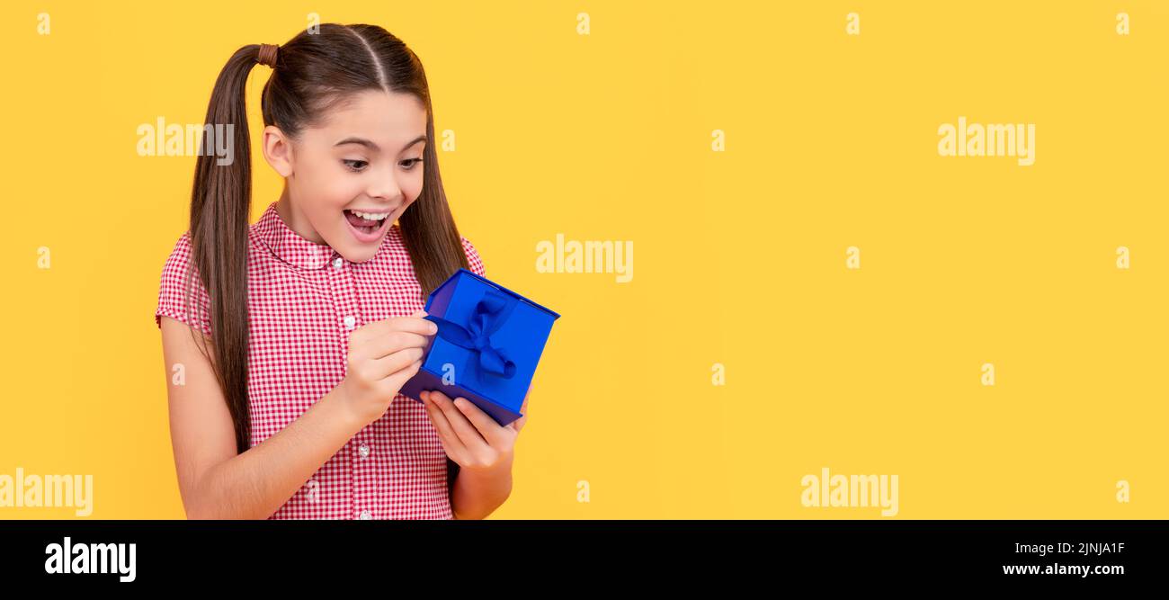 Child girl gift. surprised child hold gift box on yellow background ...