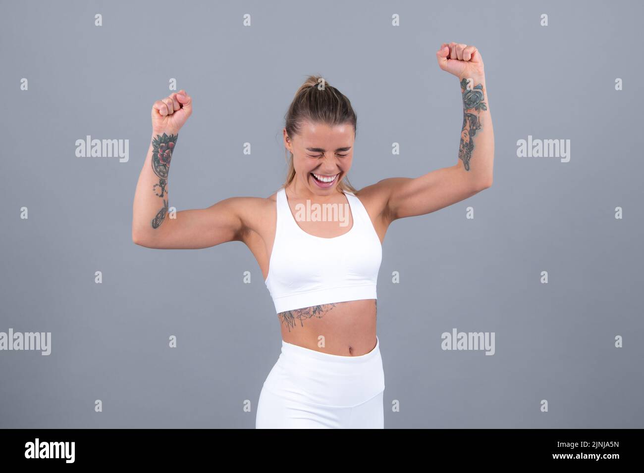 Excited sport woman showing biceps muscles. Caucasian female athlete ...
