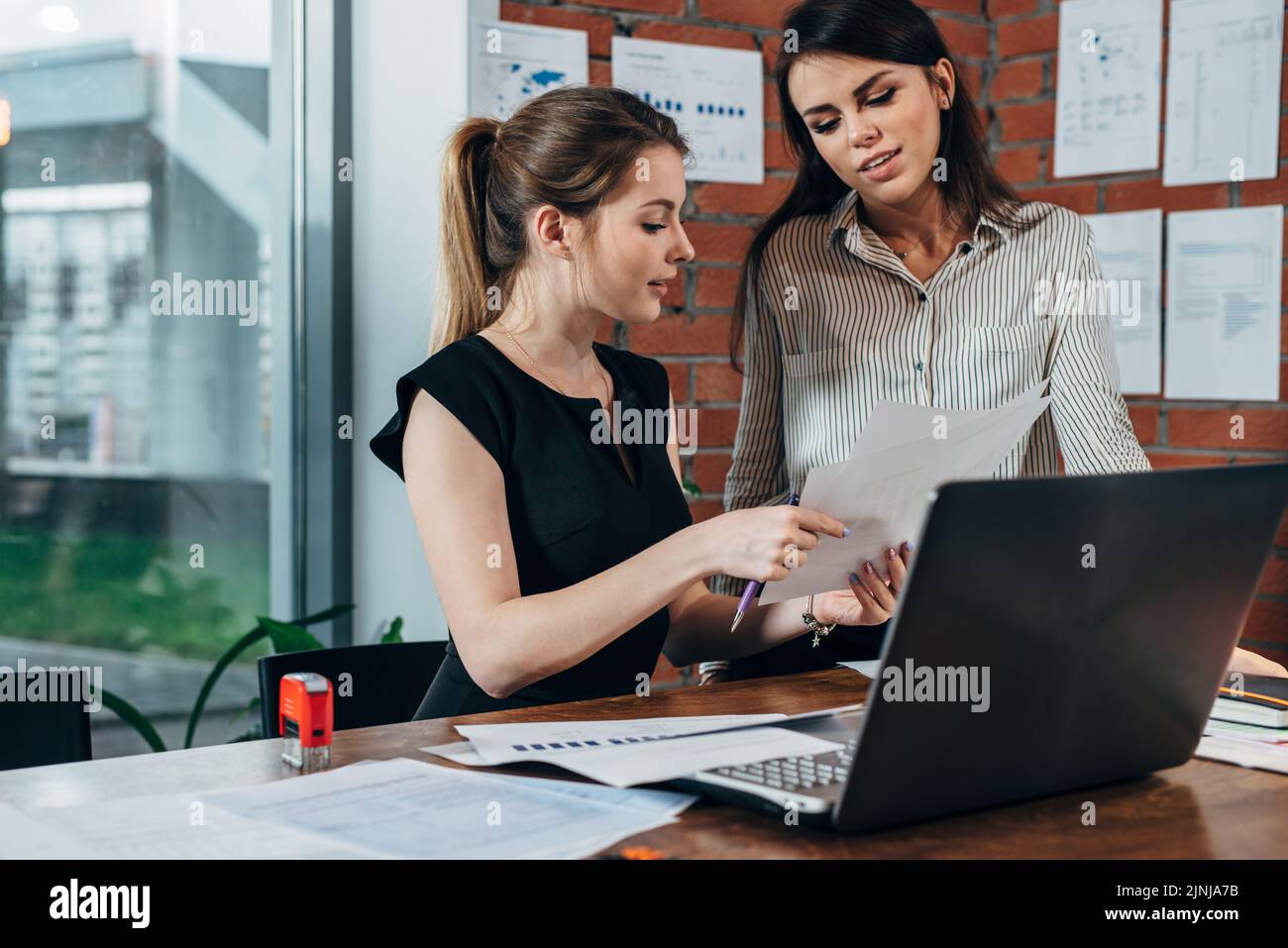 Female secretary looking concerned while her boss checking document ...