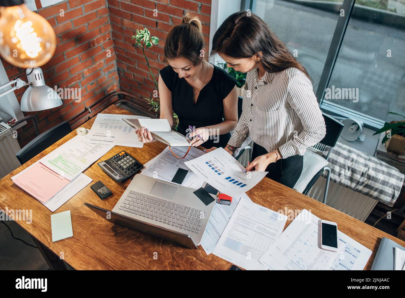 Top view of two female colleagues and desk covered with papers and ...