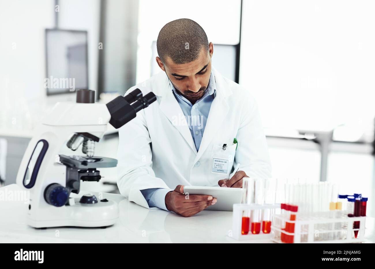 Scientist writing DNA results from microscope test on a tablet ...