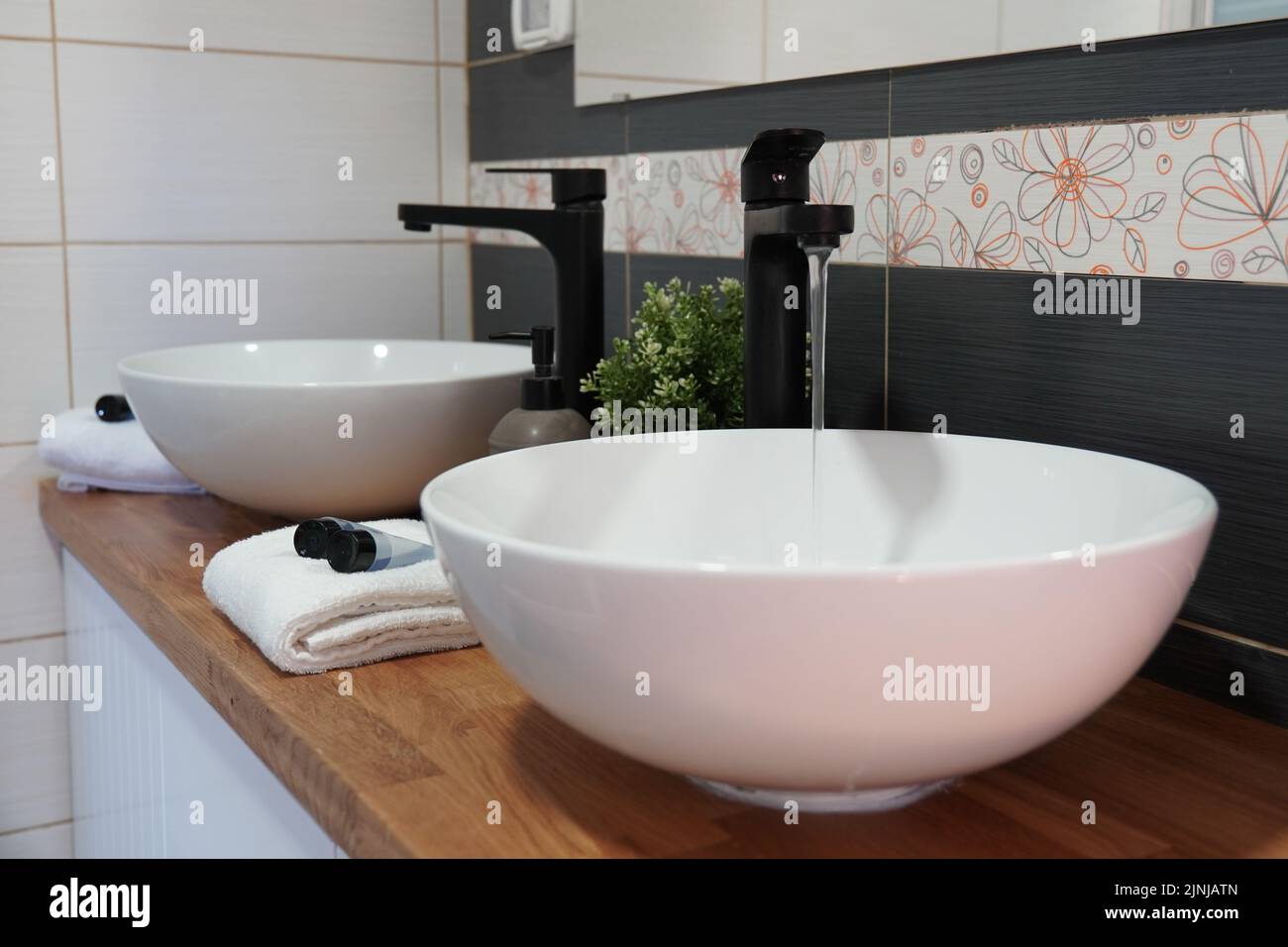 An interior view of a bathroom with water running through a tap into a ...
