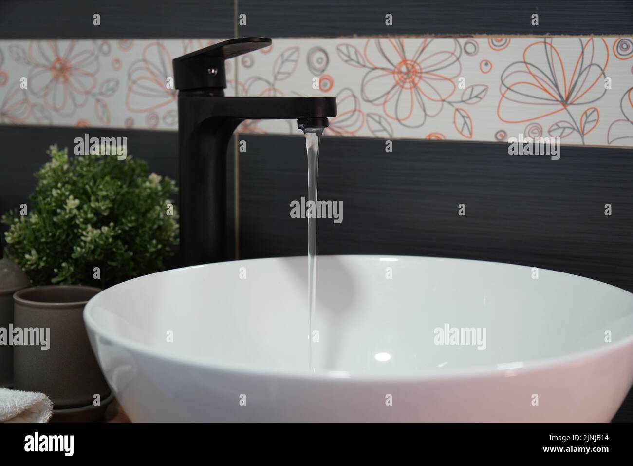 An interior view of a bathroom with water running through a tap into a ...
