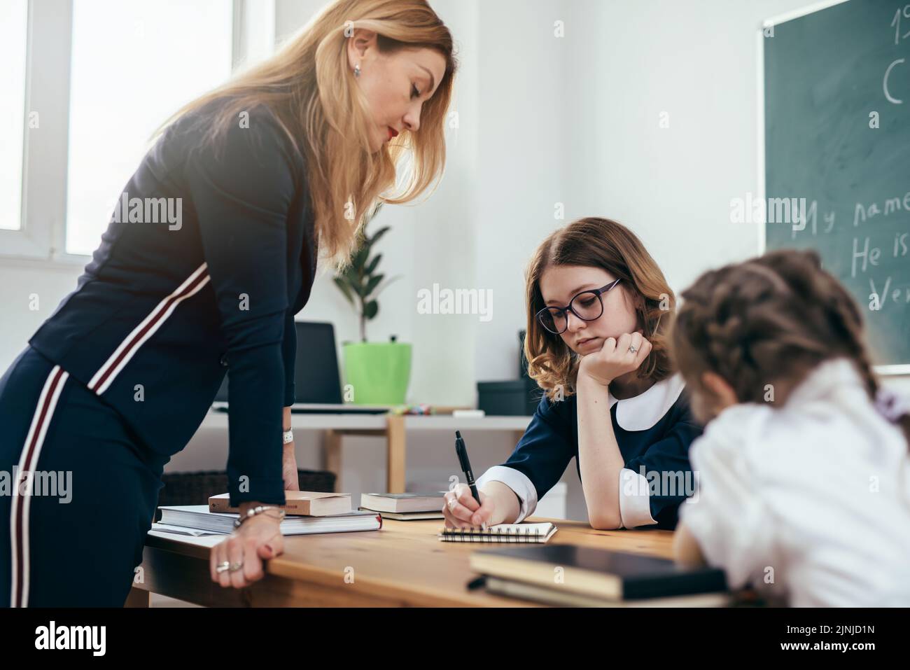Pupils and teacher reading book in classroom Stock Photo - Alamy