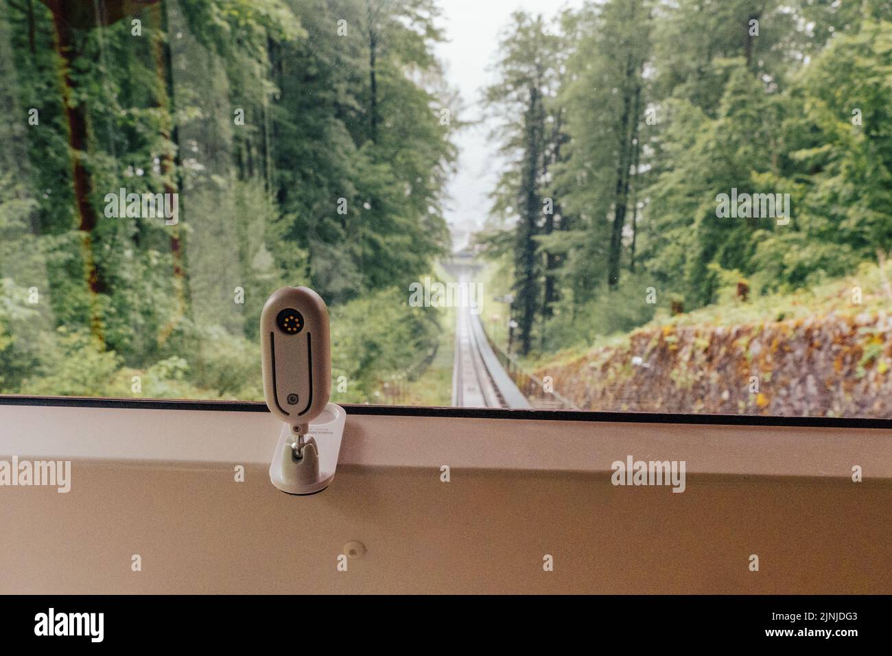 A closeup of an IP camera attached to a window viewing the green forest ...