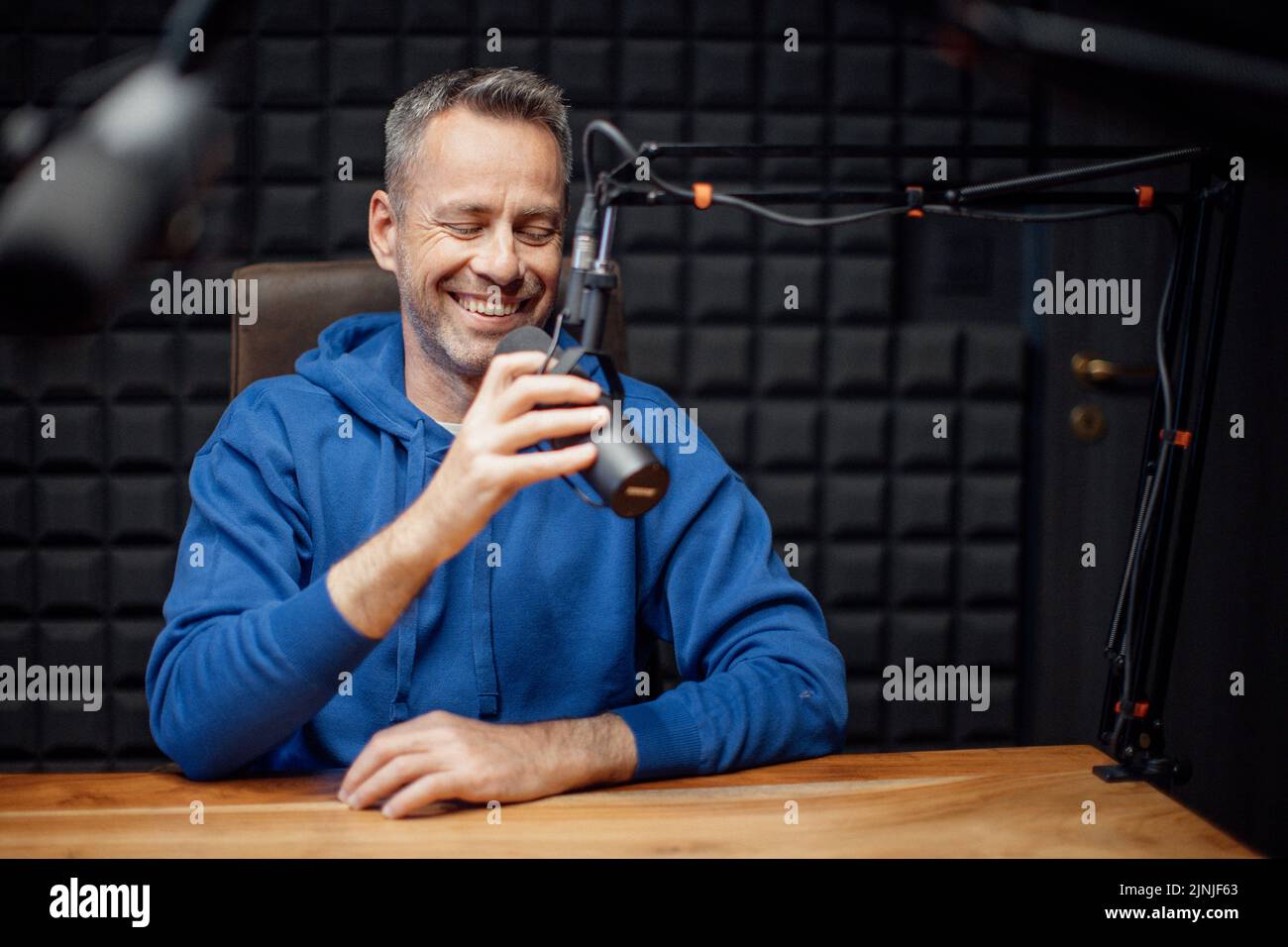 Portrait of mature radio host speaking in microphone while moderating a ...