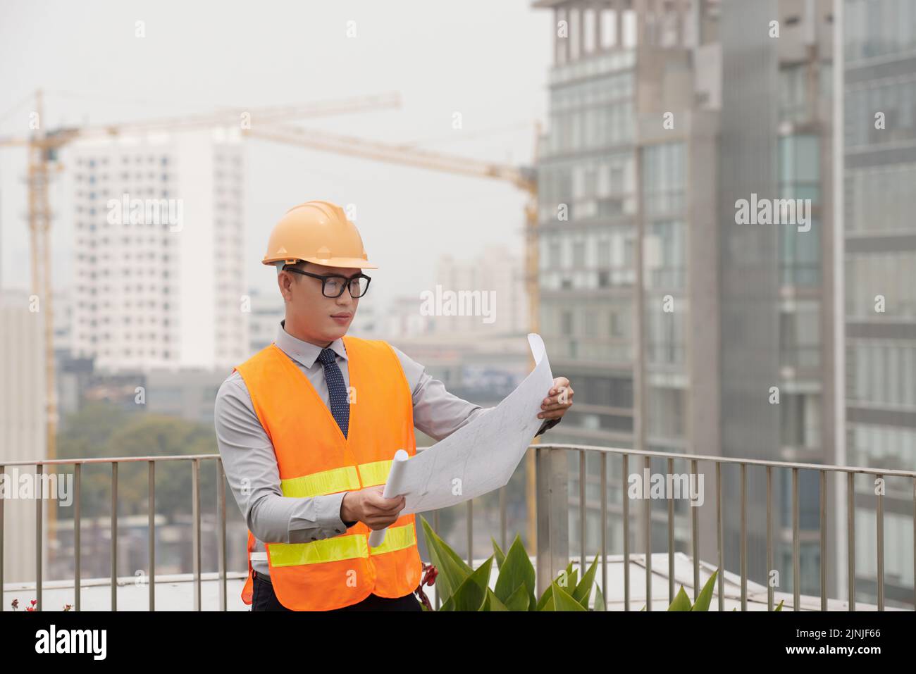 Professional young civil engineer examining blueprint in his hands ...