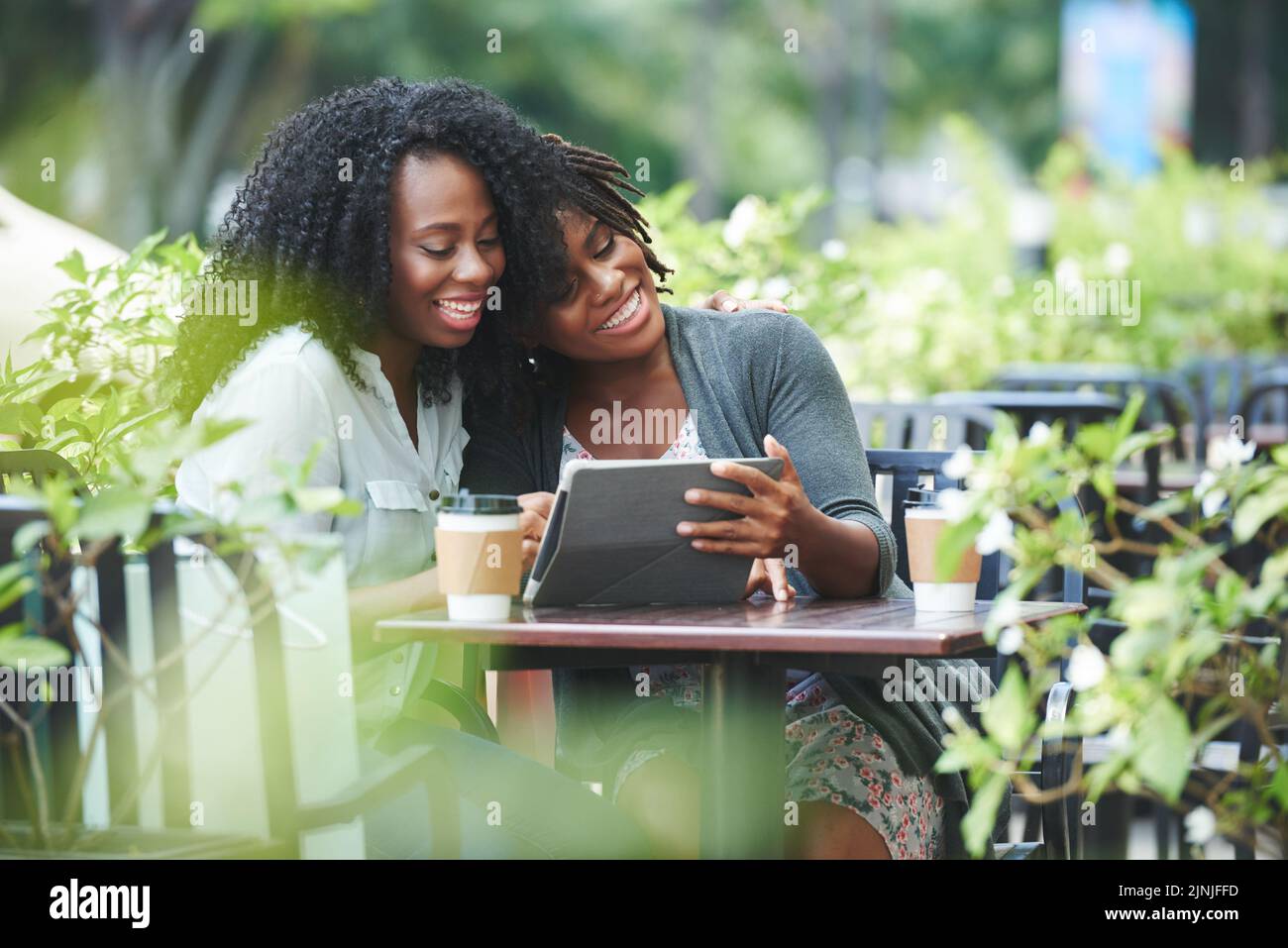Cheerful female friends spending time in outdoor cafe Stock Photo - Alamy