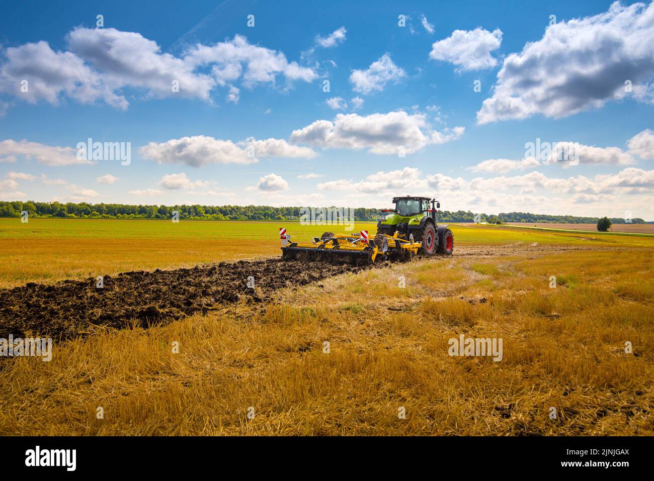 tractor with a heavy disc harrow in the field Stock Photo - Alamy