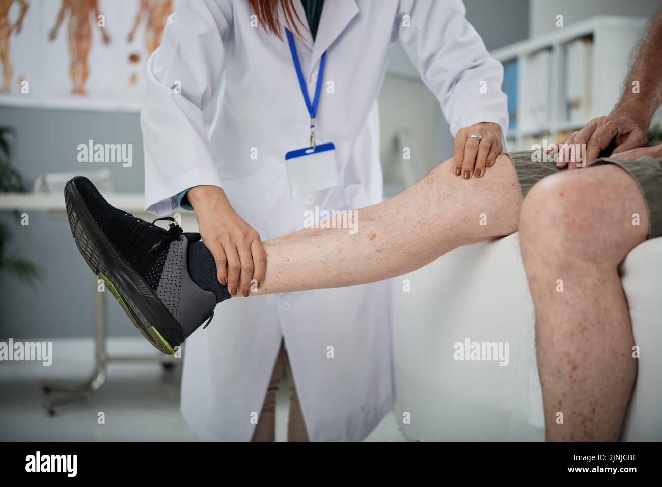Physiotherapist checking hurt leg of senior man Stock Photo - Alamy