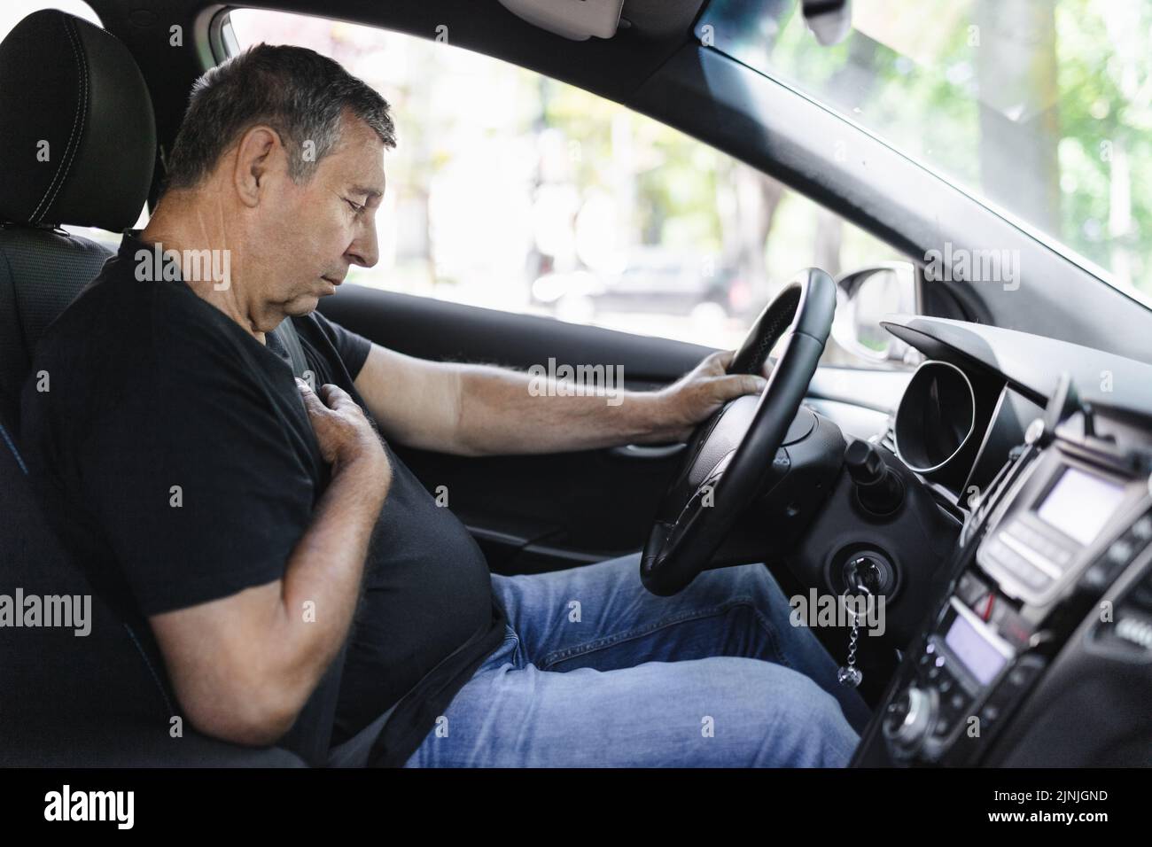 Senior in his 70s, behind the steering wheel with chest pain Stock ...