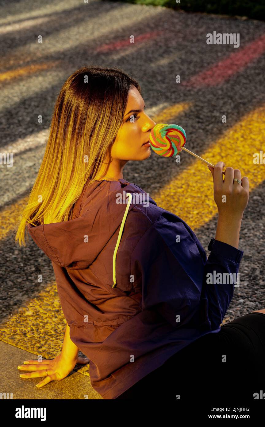 A Young woman with a purple sweater and a colorful candy lollipop near ...
