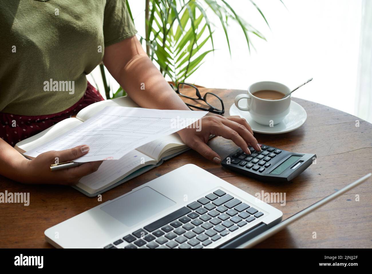 Close-up shot of unrecognizable financial manager sitting at wooden ...
