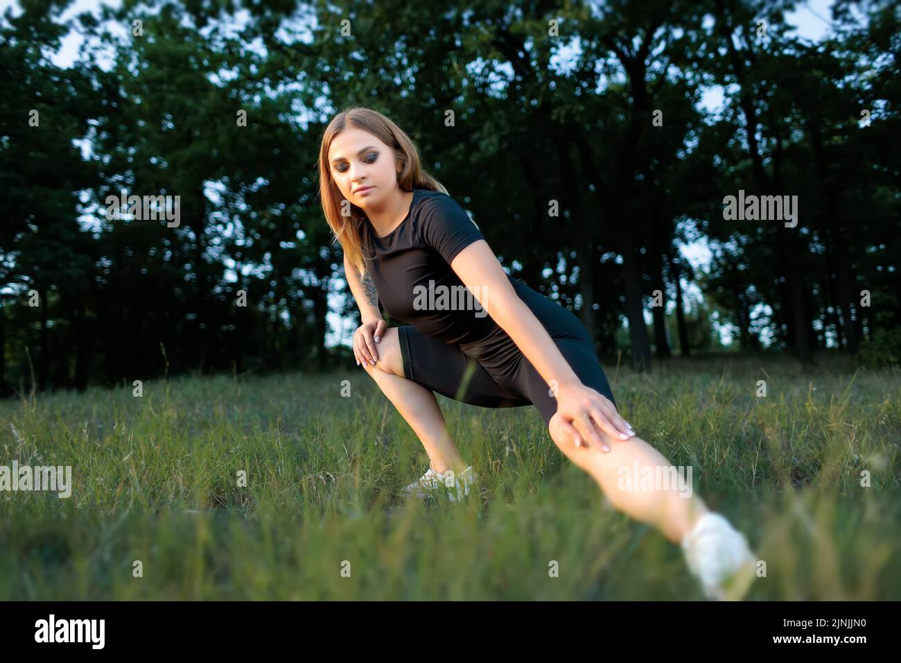 fitness blonde goes in for sports in the park doing leg stretching ...