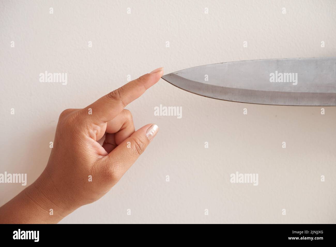Close-up shot of unrecognizable woman touching tip of knife, isolated ...