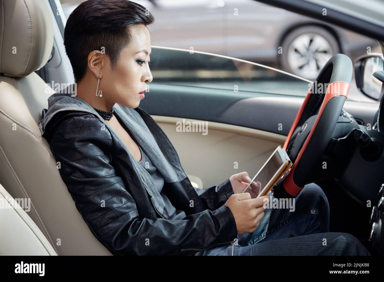 Young Asian woman setting navigation app in her tablet before driving ...