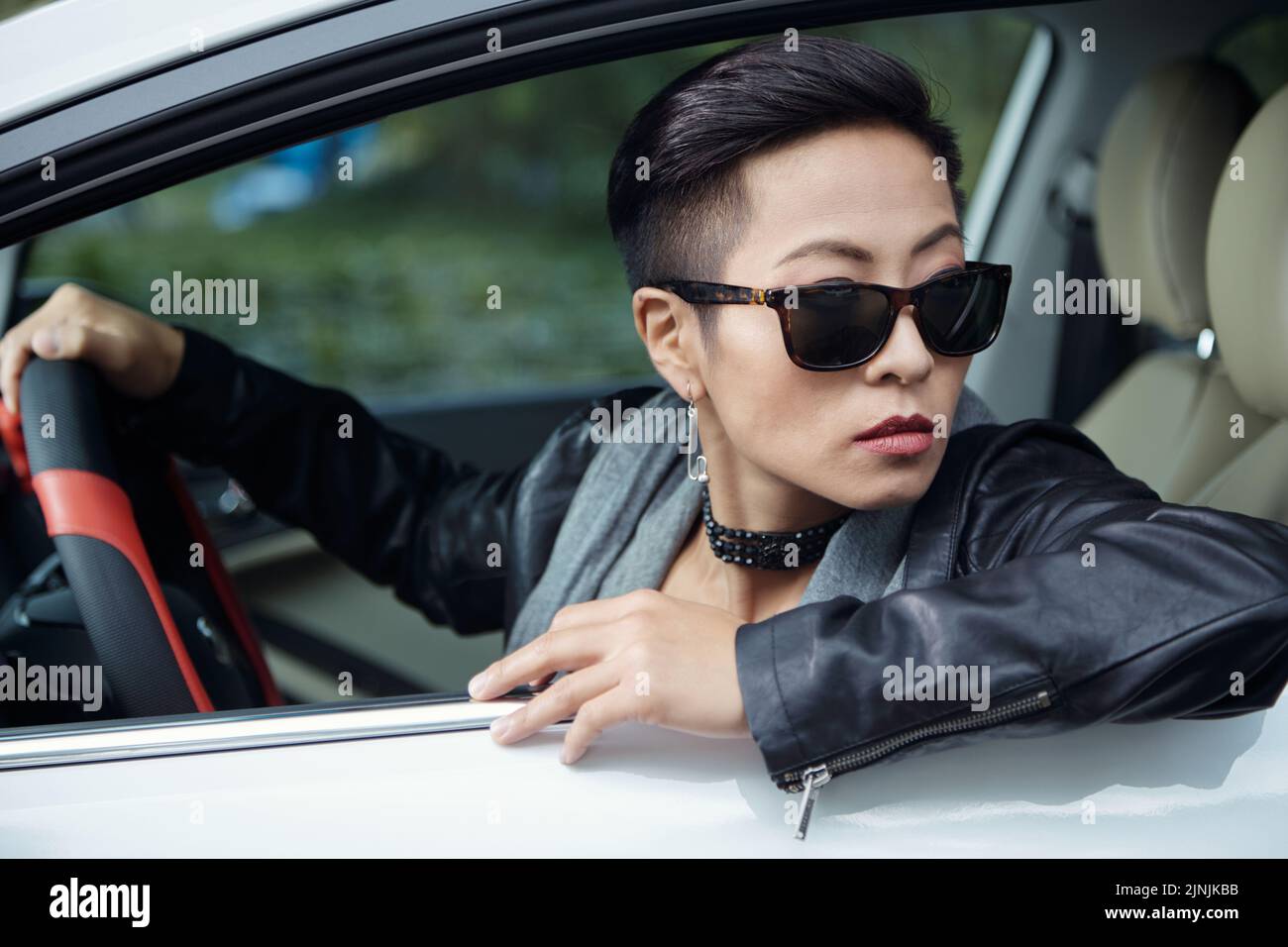 Portrait of woman in sunglasses looking out of car window Stock Photo ...