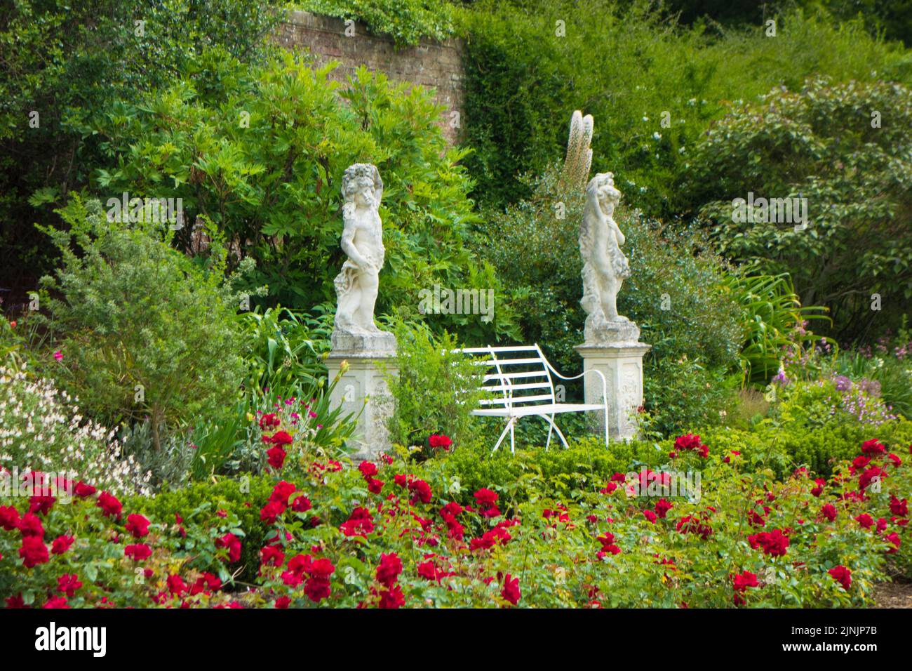 Ornate figure statues with bench seat in a rose garden Stock Photo - Alamy