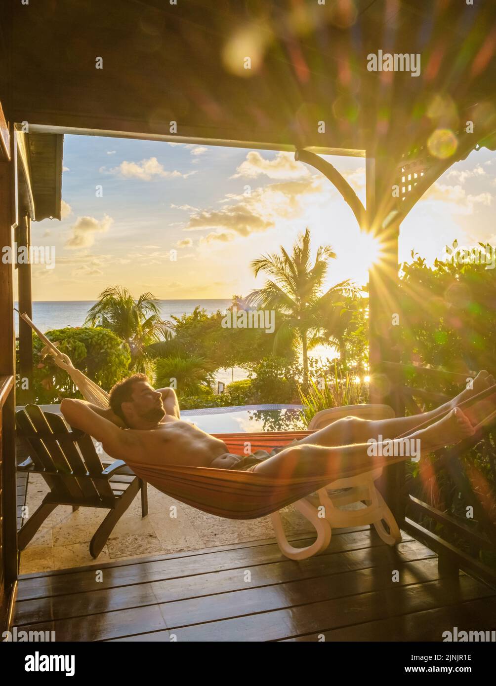 Young men in swim shorts sunbathing in a hammock at Saint Lucia ...