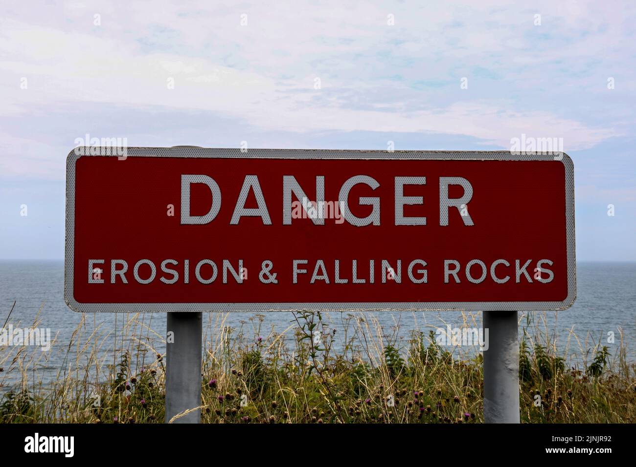 Erosion and falling rocks danger warning signboard at a coastal ...