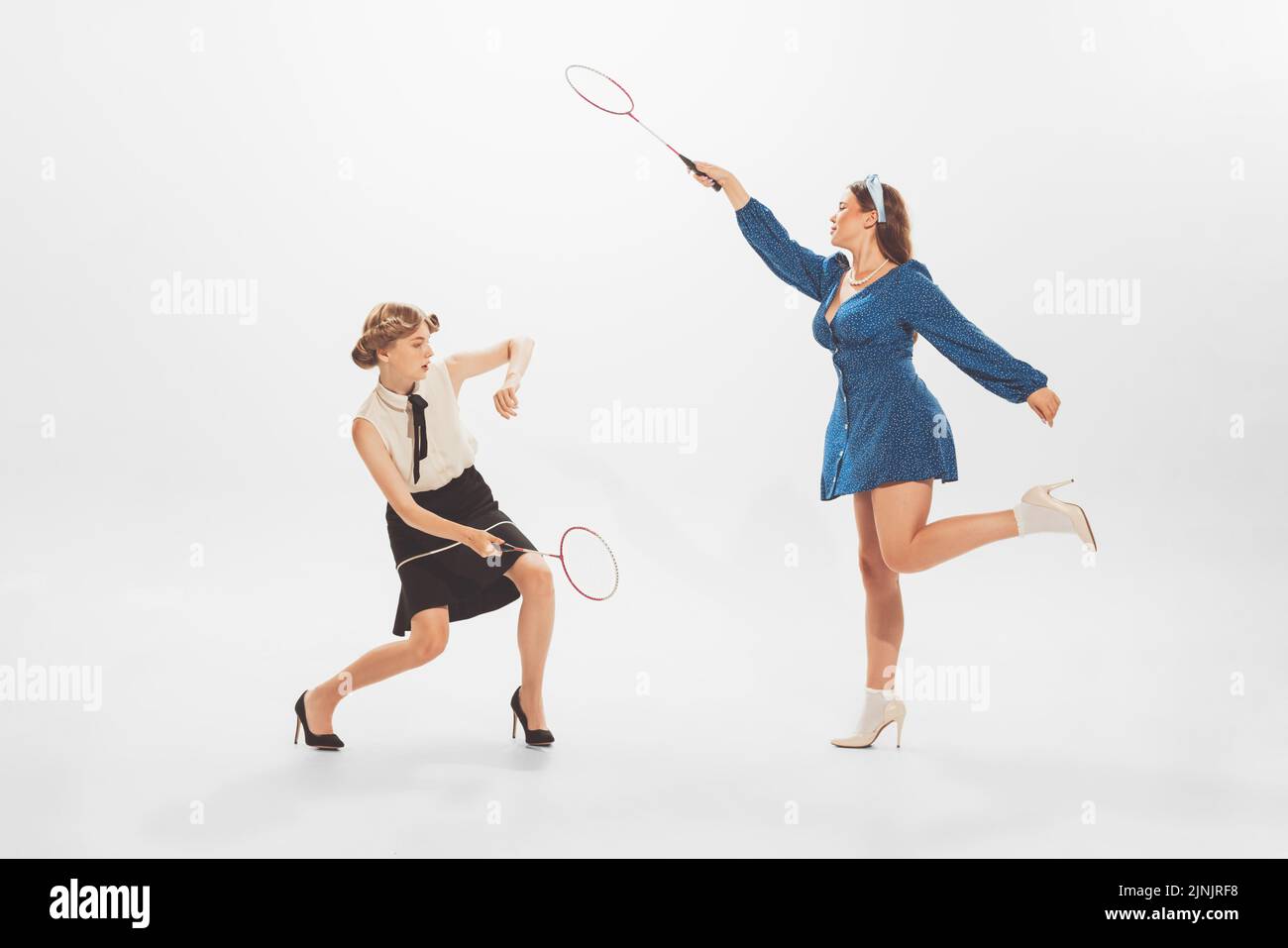 Portrait of young beautiful, stylish women playing badminton, posing ...