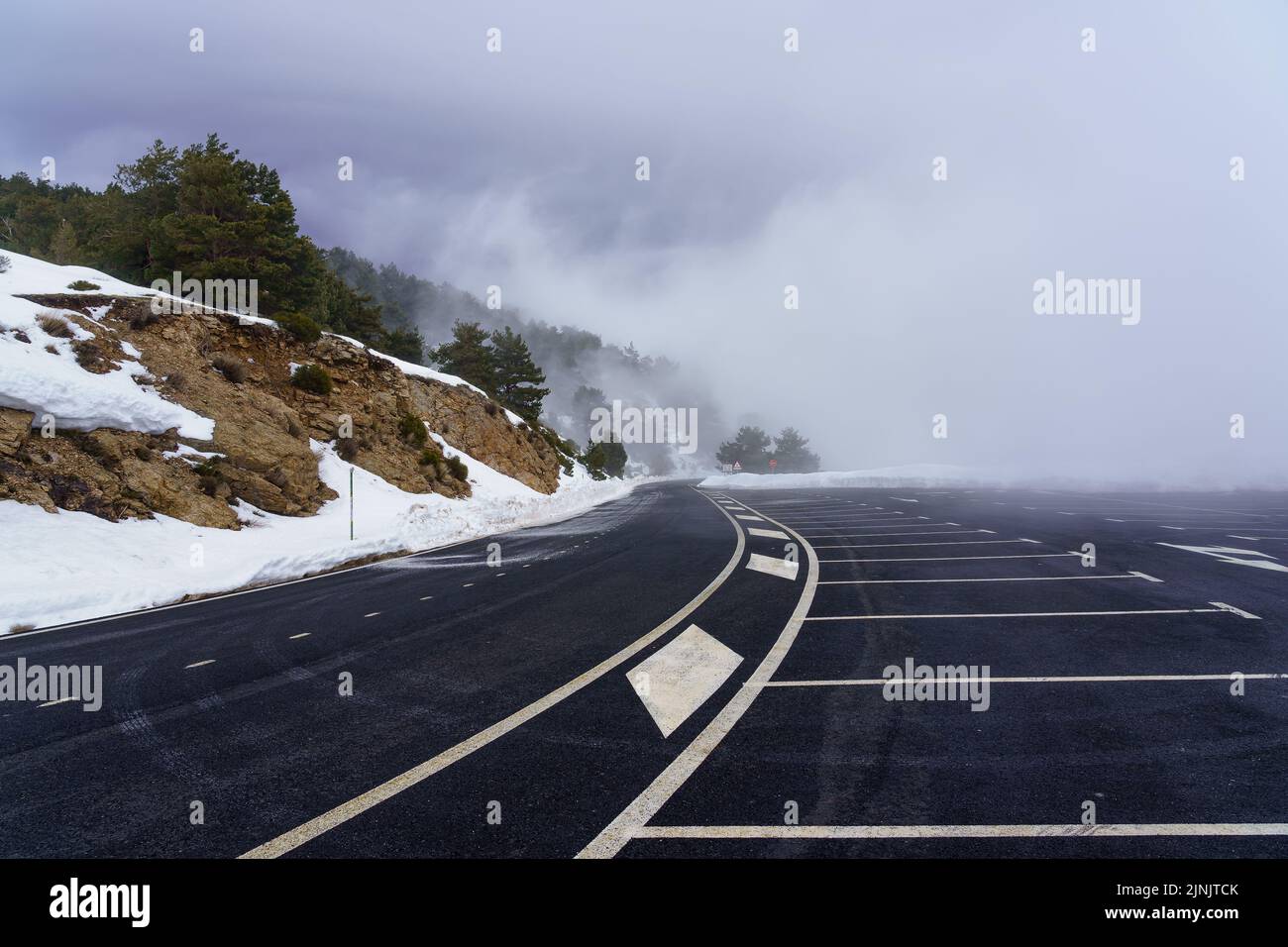 mountain road with snow and thick fog. Parking at the mountain pass ...